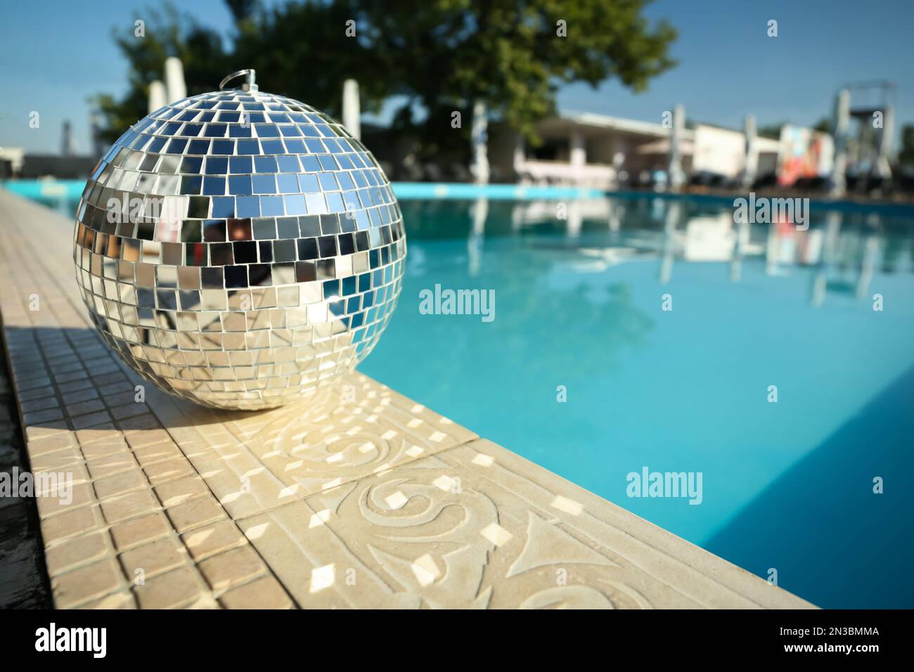 Shiny disco ball on edge of swimming pool. Party decor Stock Photo - Alamy
