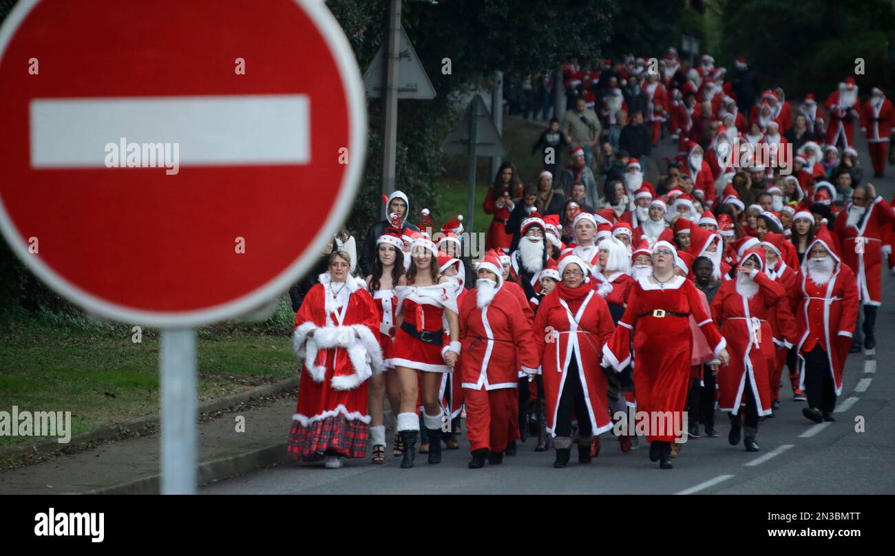 Around 250 people dressed in Santa Claus costumes parade in the streets ...