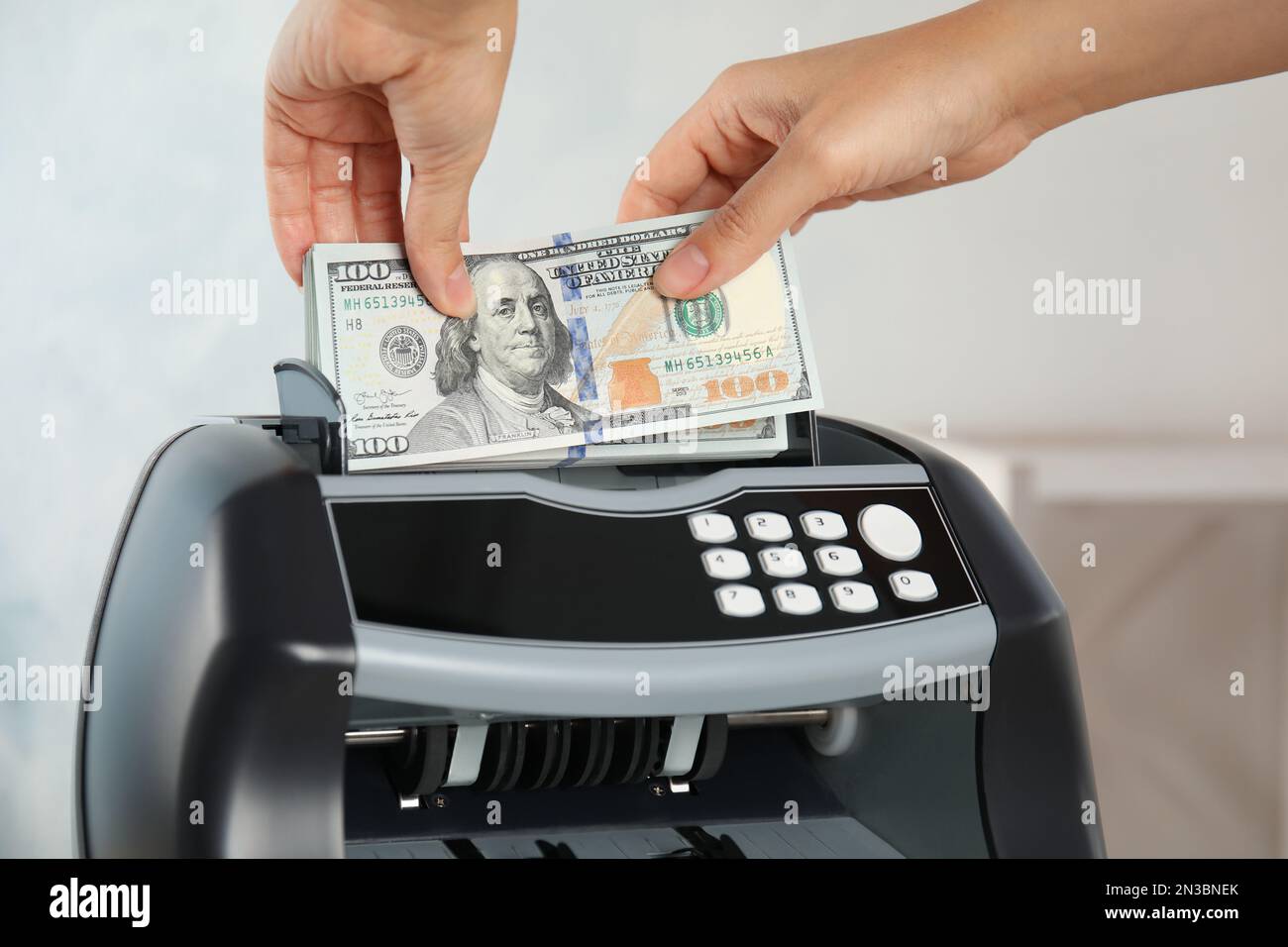 Woman putting money into counting machine indoors, closeup Stock Photo ...