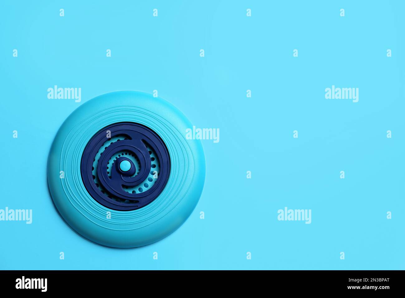 Plastic frisbee disk on light blue background, top view. Space for text ...
