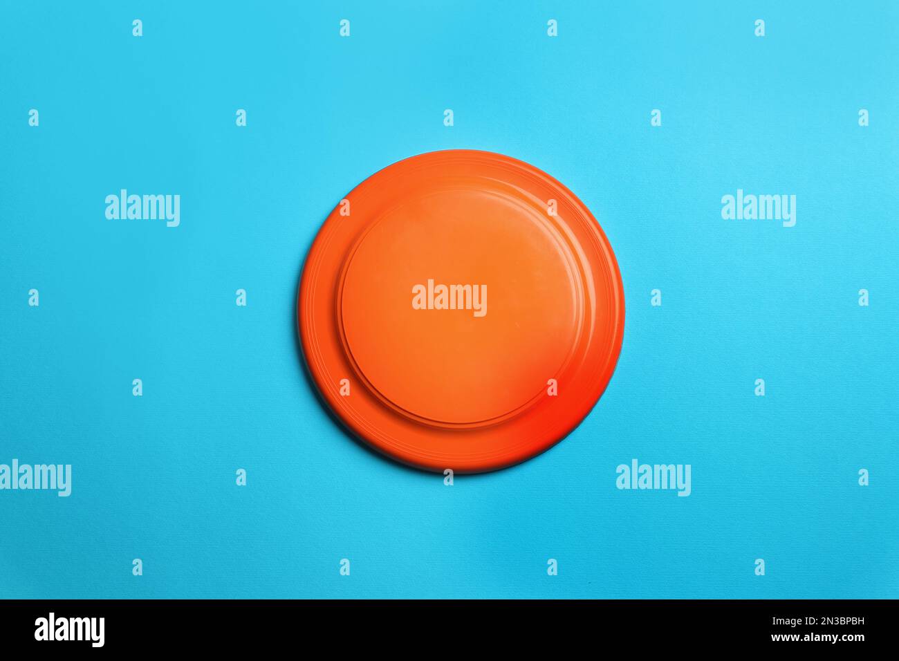 Orange plastic frisbee disk on light blue background, top view Stock ...
