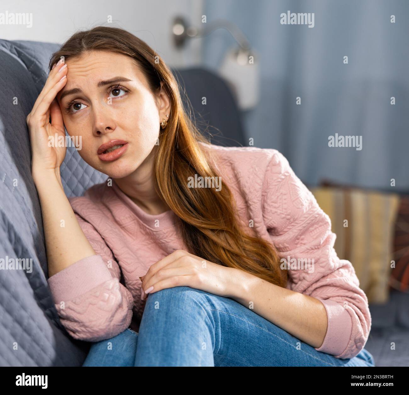 Upset woman crying while sitting on a sofa in room Stock Photo - Alamy