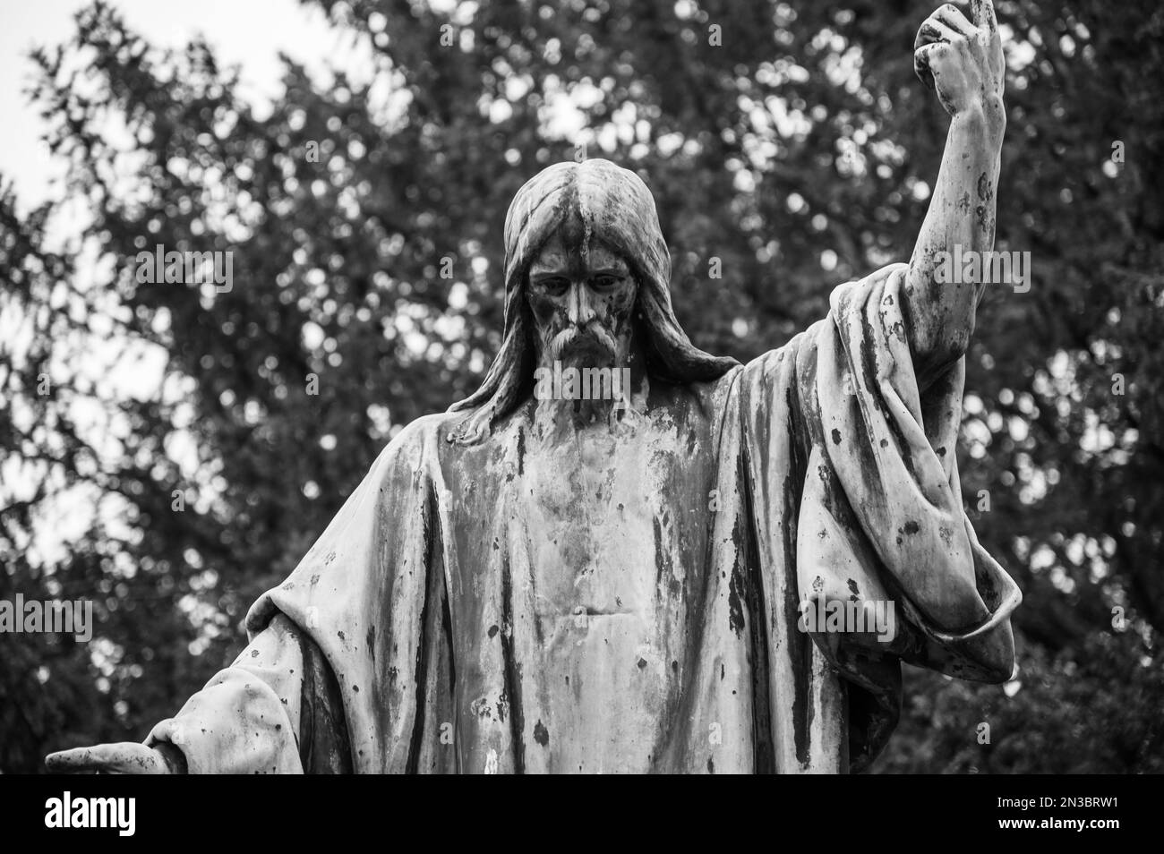 A grayscale shot of an old statue of Jesus Christ with a blurred ...