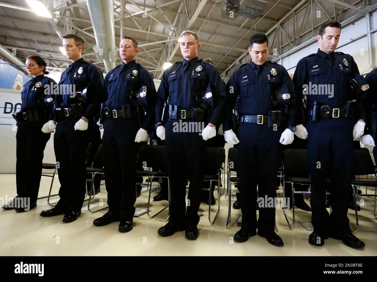 Graduating police officers bow their heads during an invocation as they ...