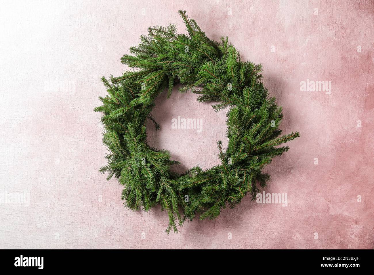 Christmas wreath made of fir branches on light pink wall Stock Photo ...