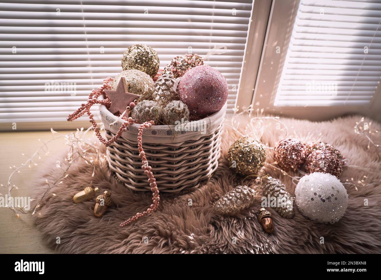 Basket with beautiful Christmas tree baubles and fairy lights on window ...