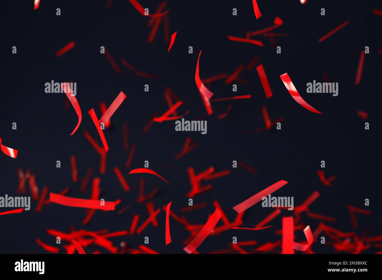 Shiny red confetti falling down on dark blue background Stock Photo - Alamy