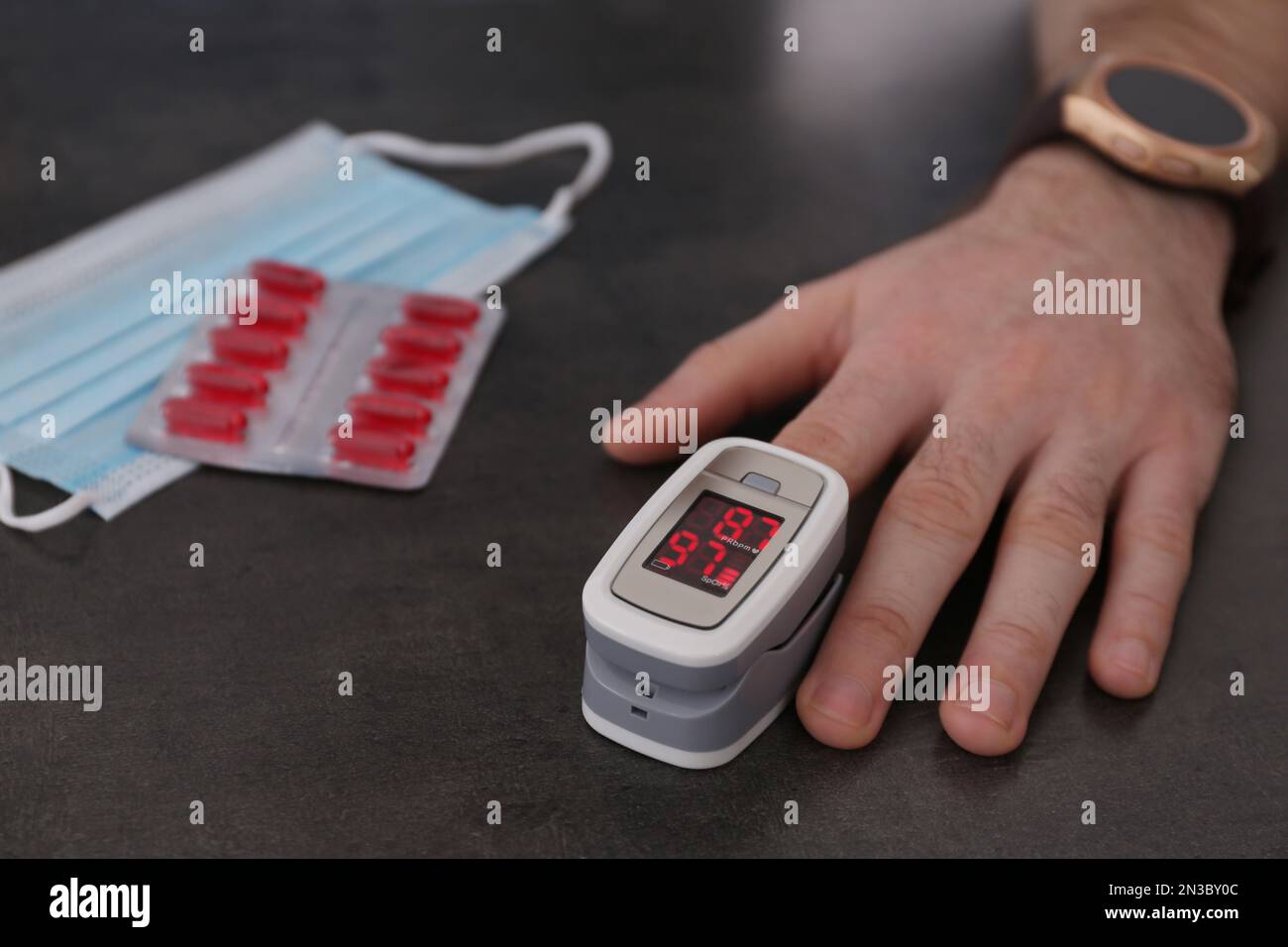 Man measuring oxygen level with modern fingertip pulse oximeter at grey ...