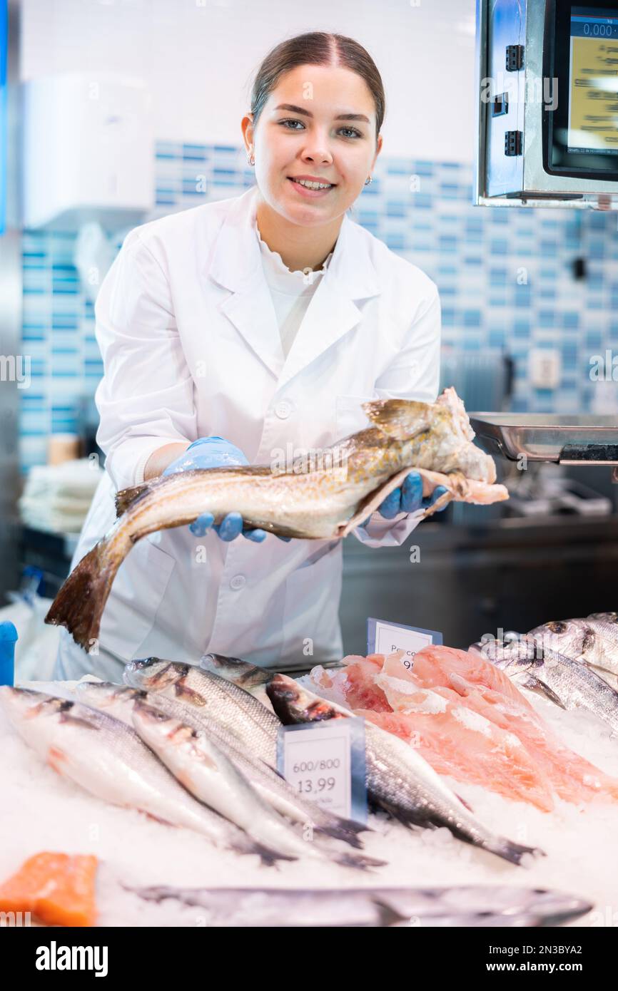 Portrait of saleswoman offering fresh fish atlantic cod at shop Stock Photo - Alamy