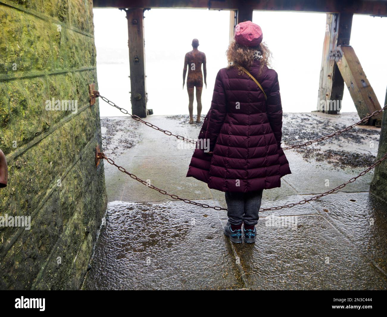 View taken from behind of a woman posing as Antony Gormley's cast iron ...