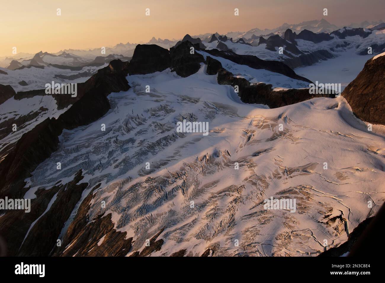 Warm light of the setting sun highlights jagged peaks of granite ...