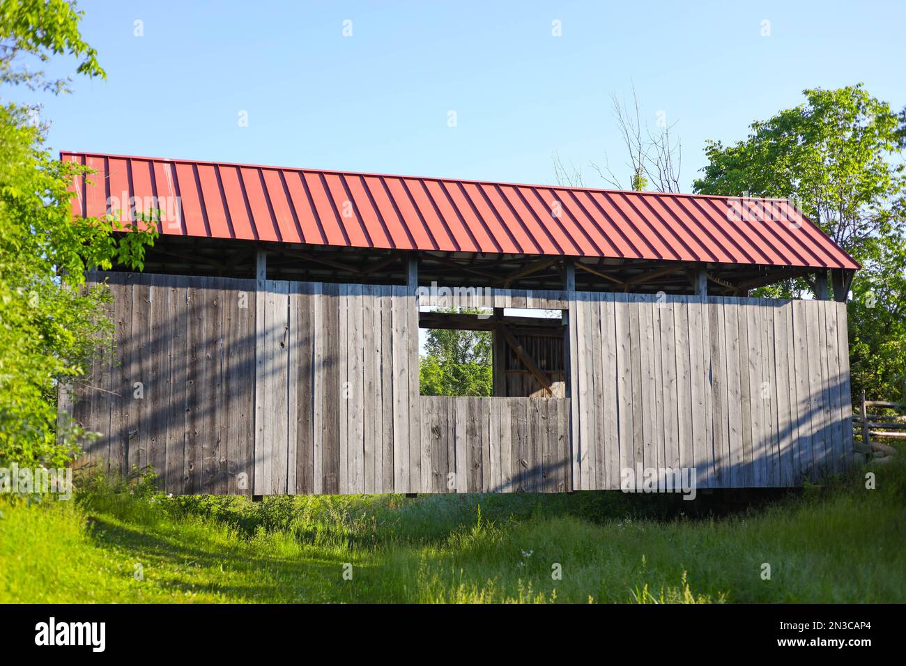 A wooden covered bridge with red metal roof in Slate run metro Park ...