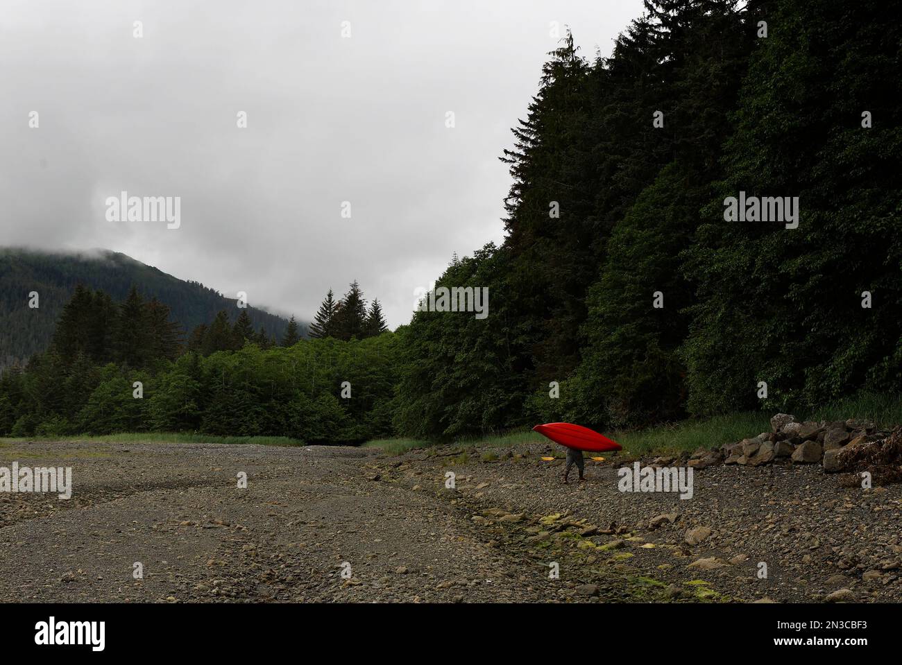 A kayaker carries his boat to higher ground to explore the wilderness ...