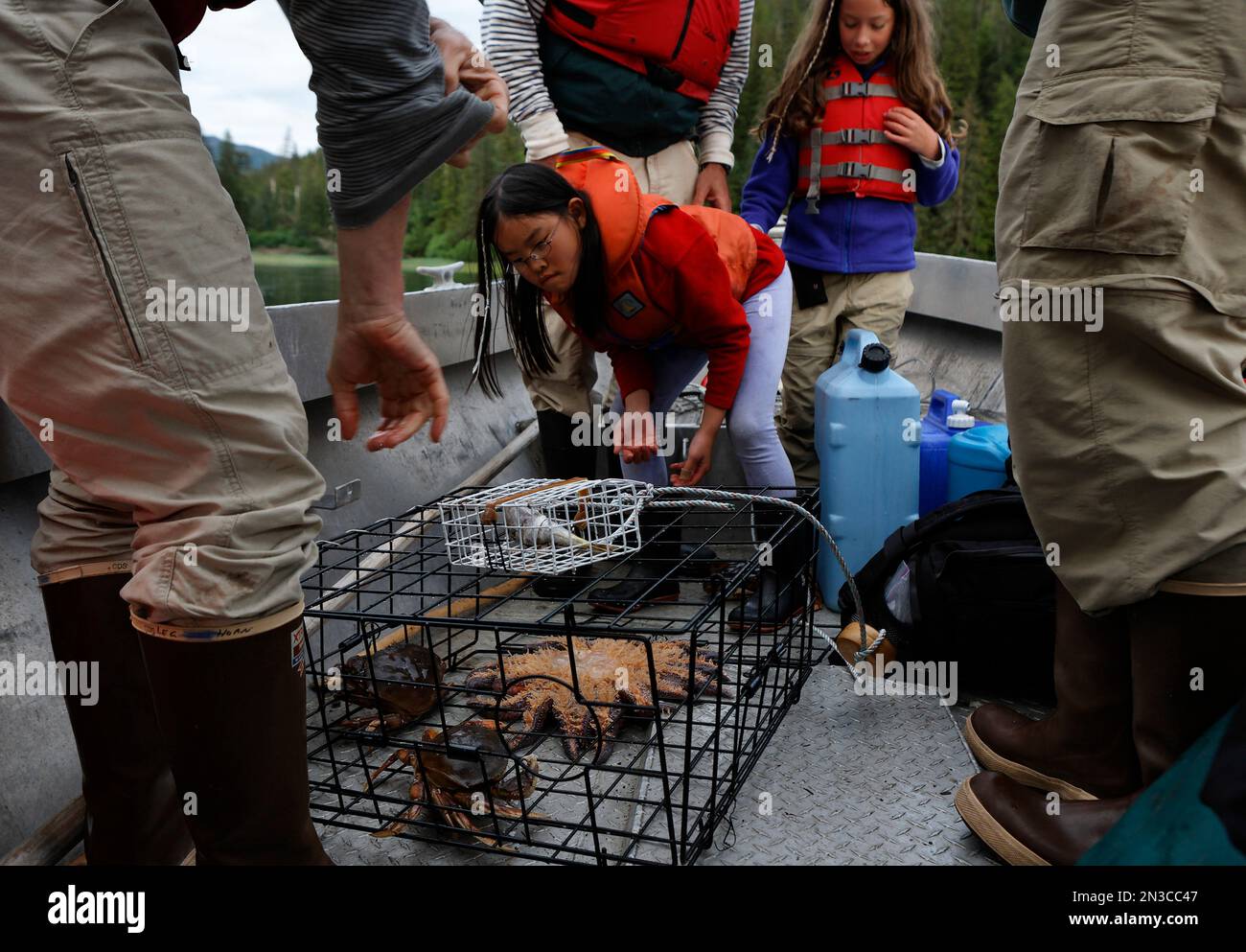 Families gather for a boat ride and check a crab pot that also ...