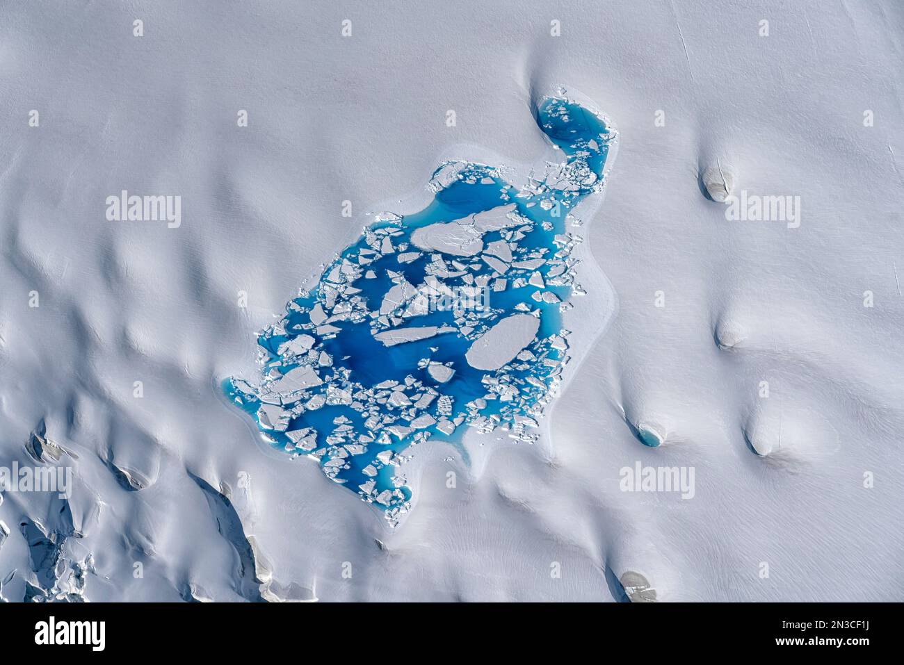 Aerial view of the snow-covered ice mass with a glacial lake in the ...