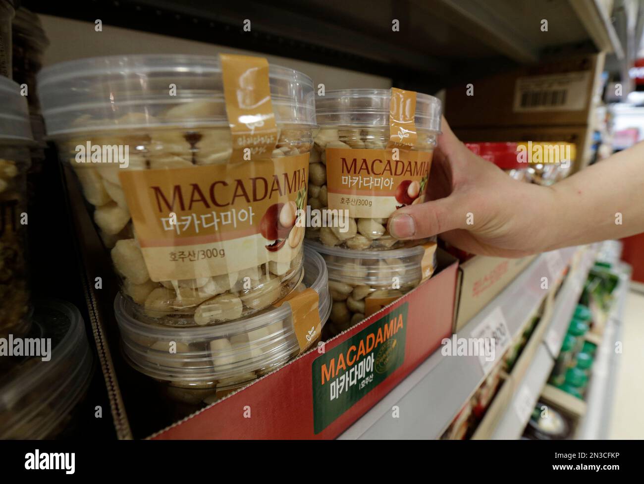 A customer picks up a plastic container of Macadamia nuts at a store in ...