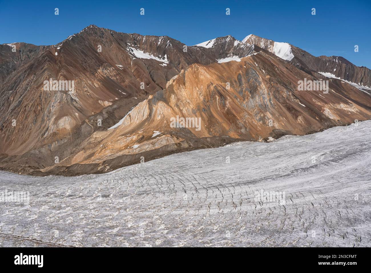 Aerial view of the silt covered mountain peaks and the grey ice of a ...