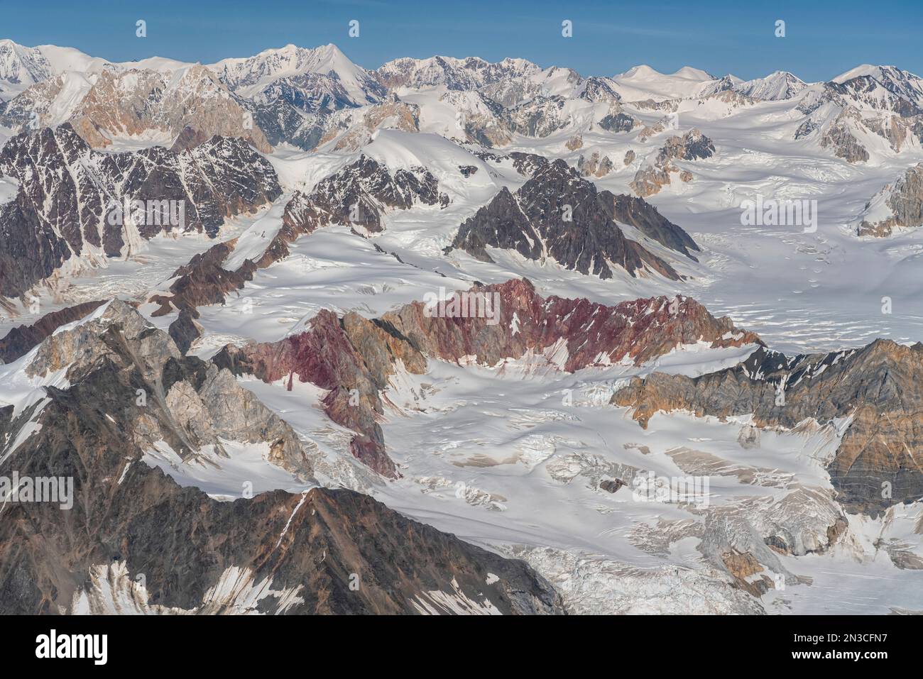Aerial view of the jagged mountain peaks revealing red rock faces and ...