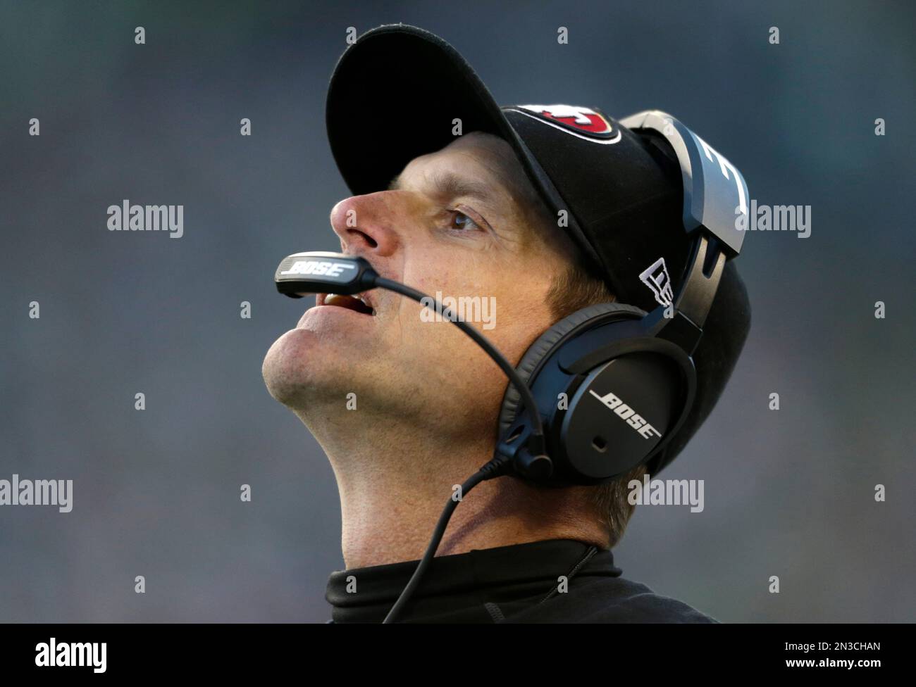 San Francisco 49ers head coach Jim Harbaugh wears a headset on the ...