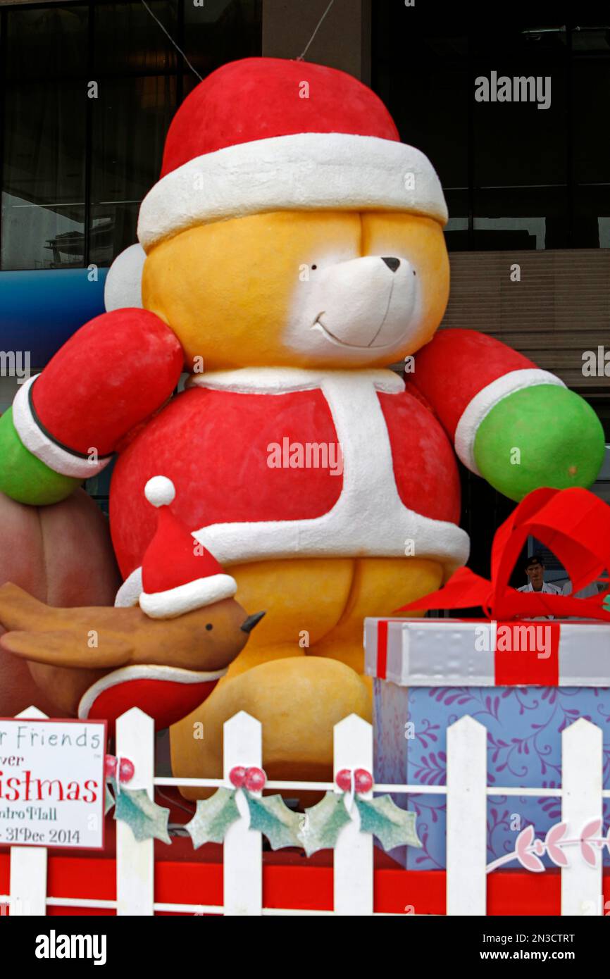 A security guard stands behind a giant bear model in Santa costume on ...