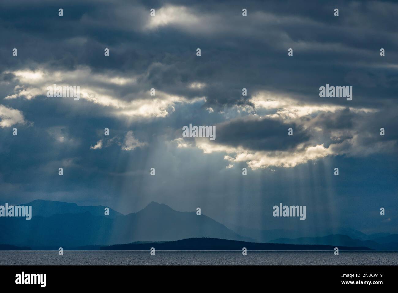 Sun breaking through rain clouds in the Chatham Strait area of Southeast Alaska; Alaska, United ...
