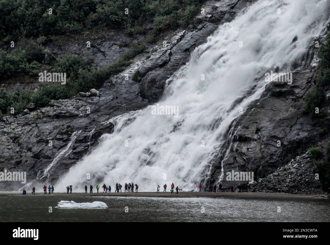Tourists watch the forceful flow of Nugget Falls at the base of Bullard ...