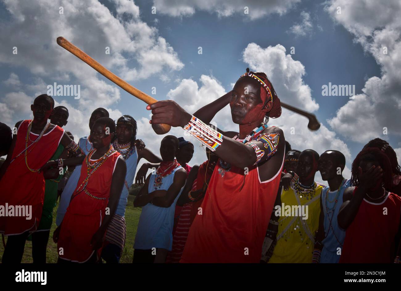 A Maasai warrior holds up his stick to line his sight, left, as he ...