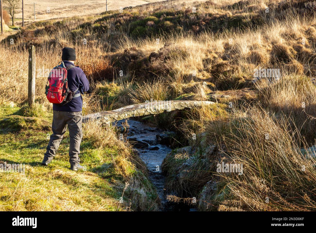 Backpacker standing by an old packhorse bridge near Flash in the ...
