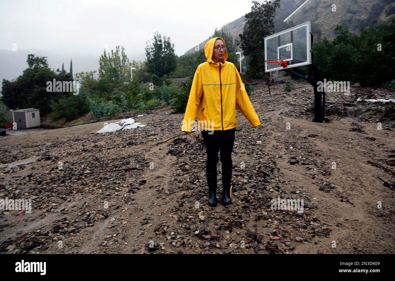 Homeowner Amanda Heinlein stands on a mud landslide covering a ...