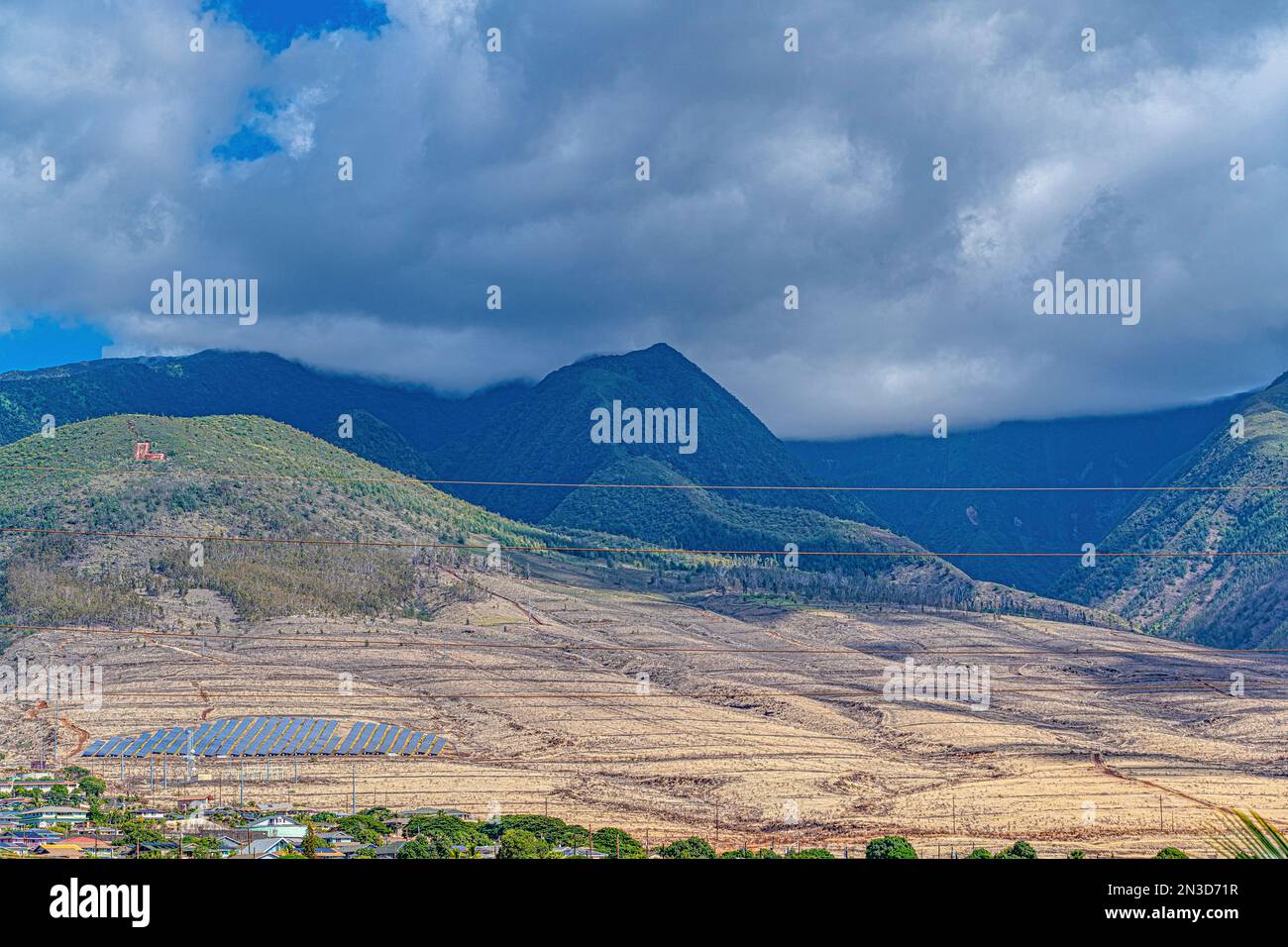Solar panels and power lines on the mountainside over the rooftops of ...