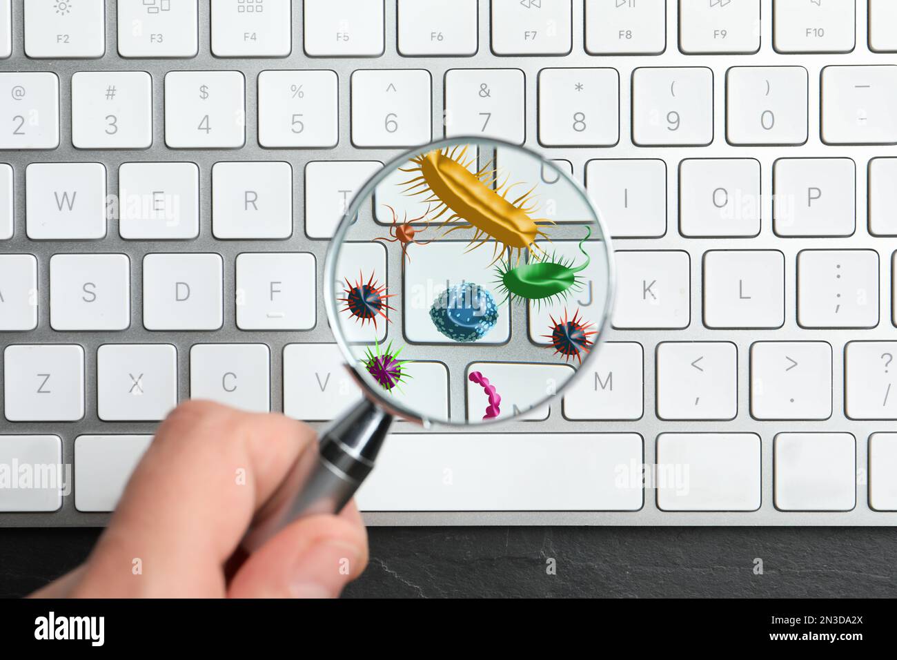 Woman with magnifying glass detecting microbes on keyboard, closeup ...