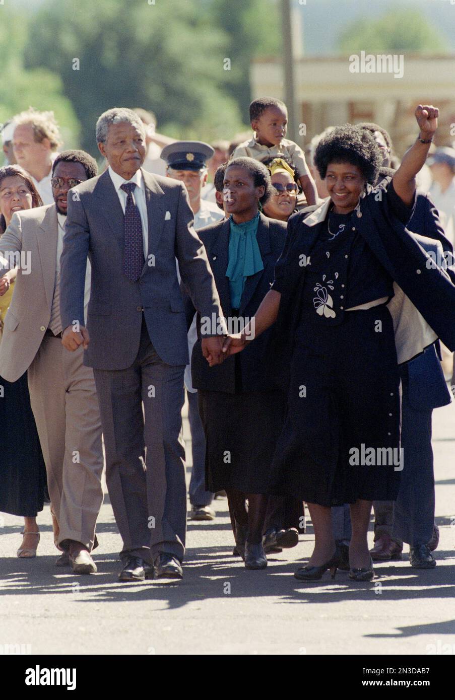 Nelson Mandela is led by his wife Winnie, raising her fist in ...