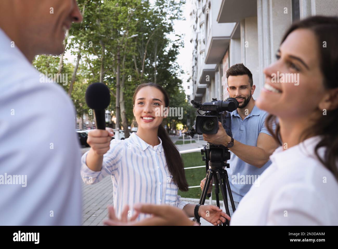 Professional journalist and operator with video camera taking interview ...