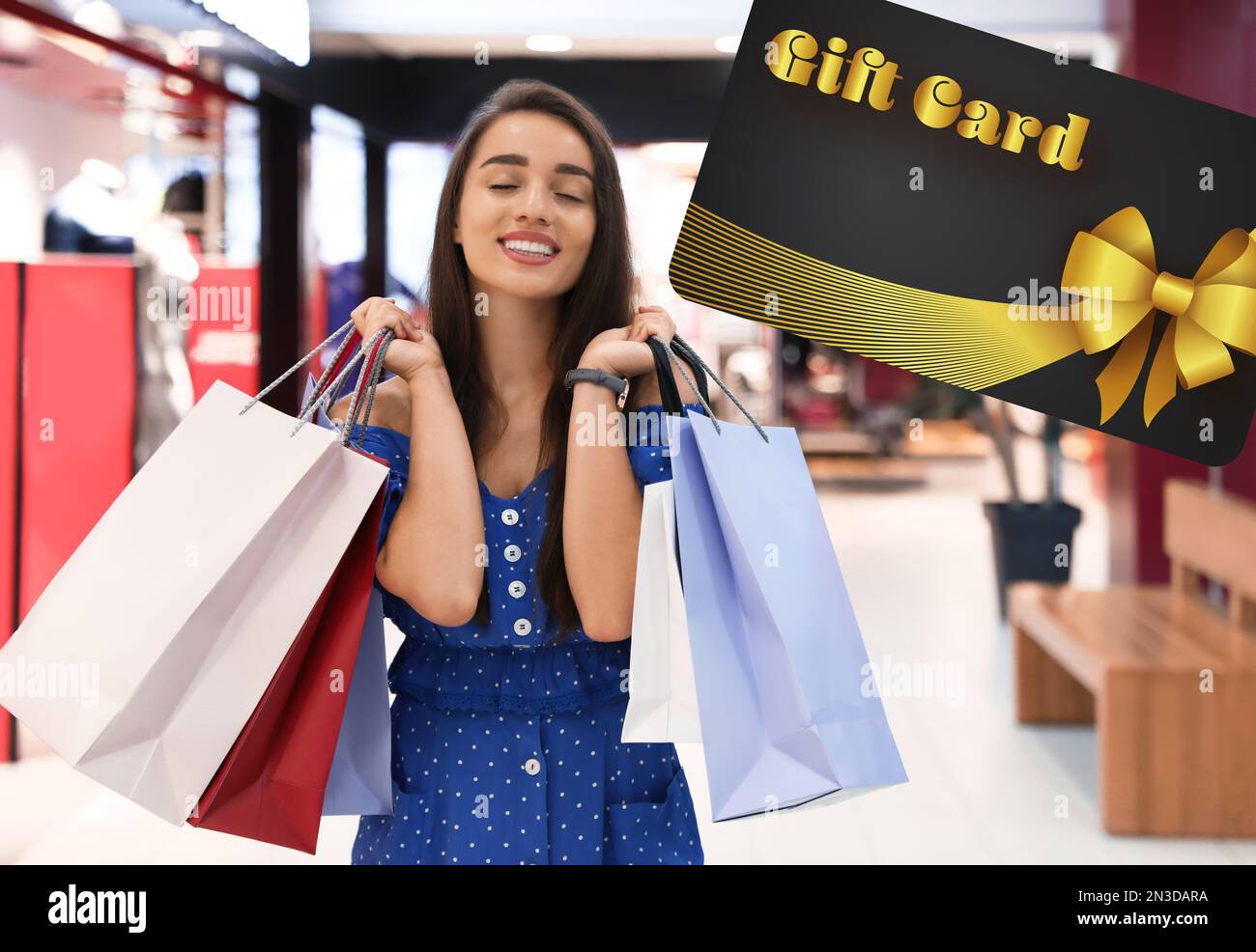 Store gift card. Happy young woman with shopping bags in mall Stock ...