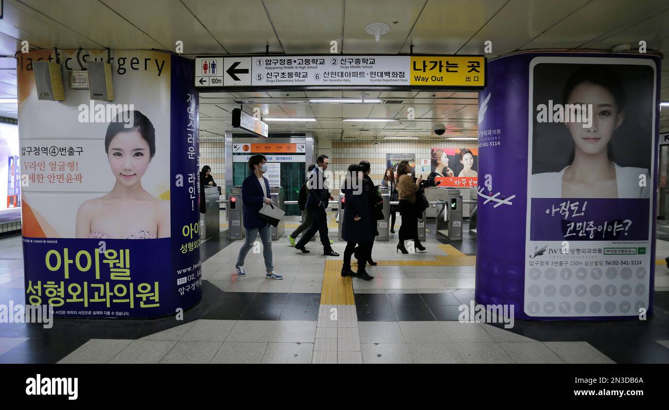 In this Friday, Nov. 21, 2014 photo, people pass by posters advertising ...