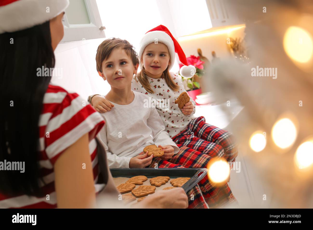 Mother giving her cute little children freshly baked Christmas cookies ...