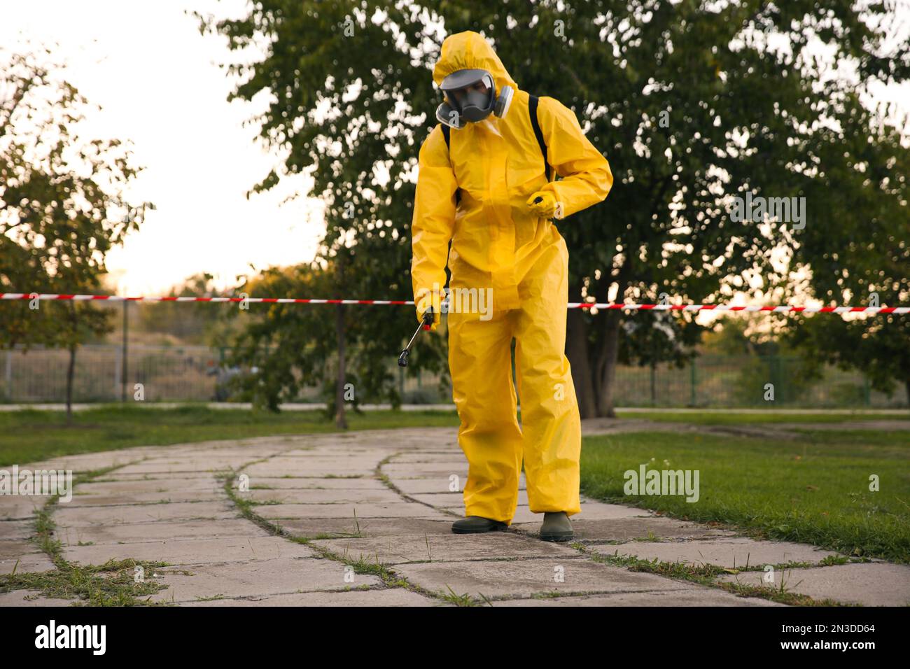 Person in hazmat suit disinfecting street pavement with sprayer ...