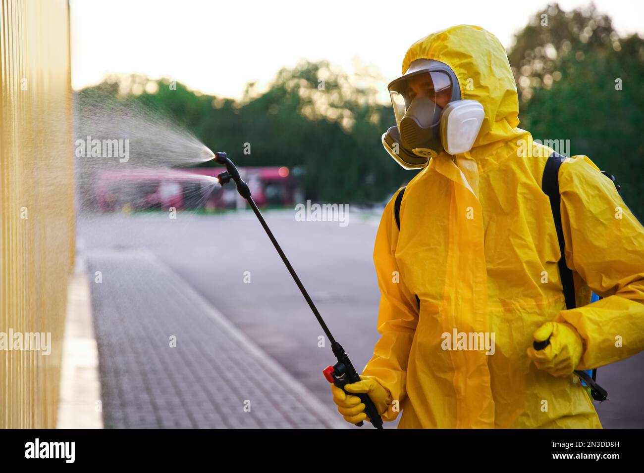 Person in hazmat suit disinfecting street with sprayer. Surface ...