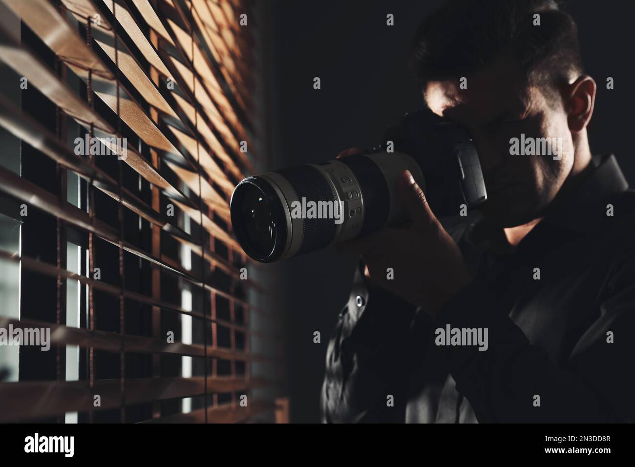 Private detective with camera spying near window indoors Stock Photo ...