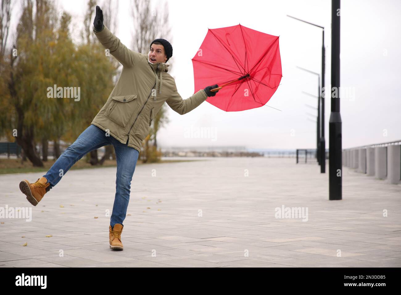 Man with red umbrella caught in gust of wind outdoors Stock Photo - Alamy