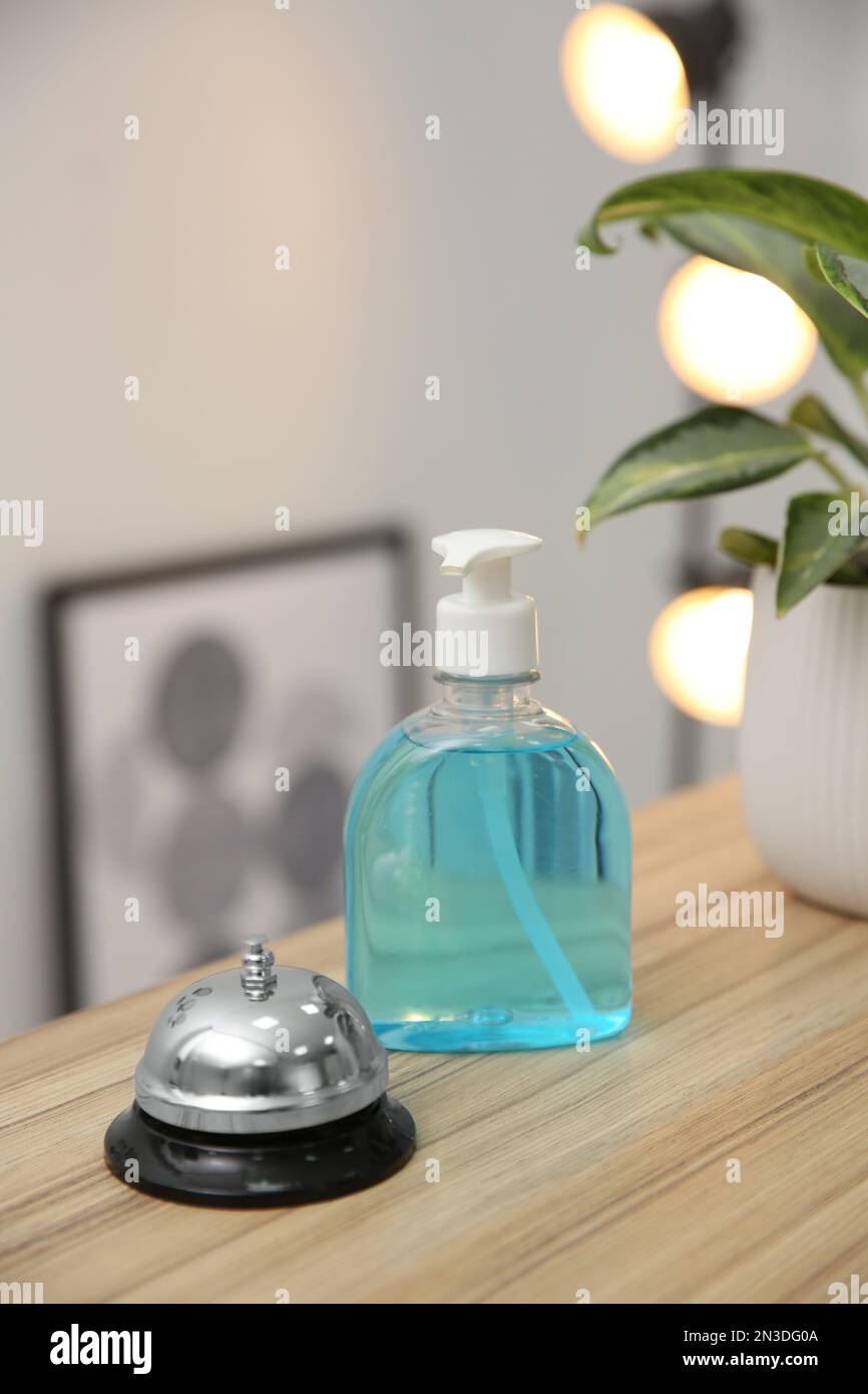 Dispenser bottle of antiseptic gel and service bell on reception desk ...