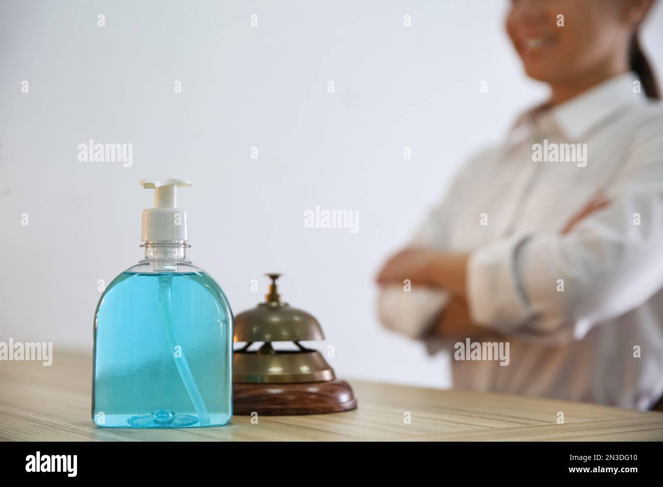 Receptionist at countertop in hotel, focus on dispenser bottle with ...