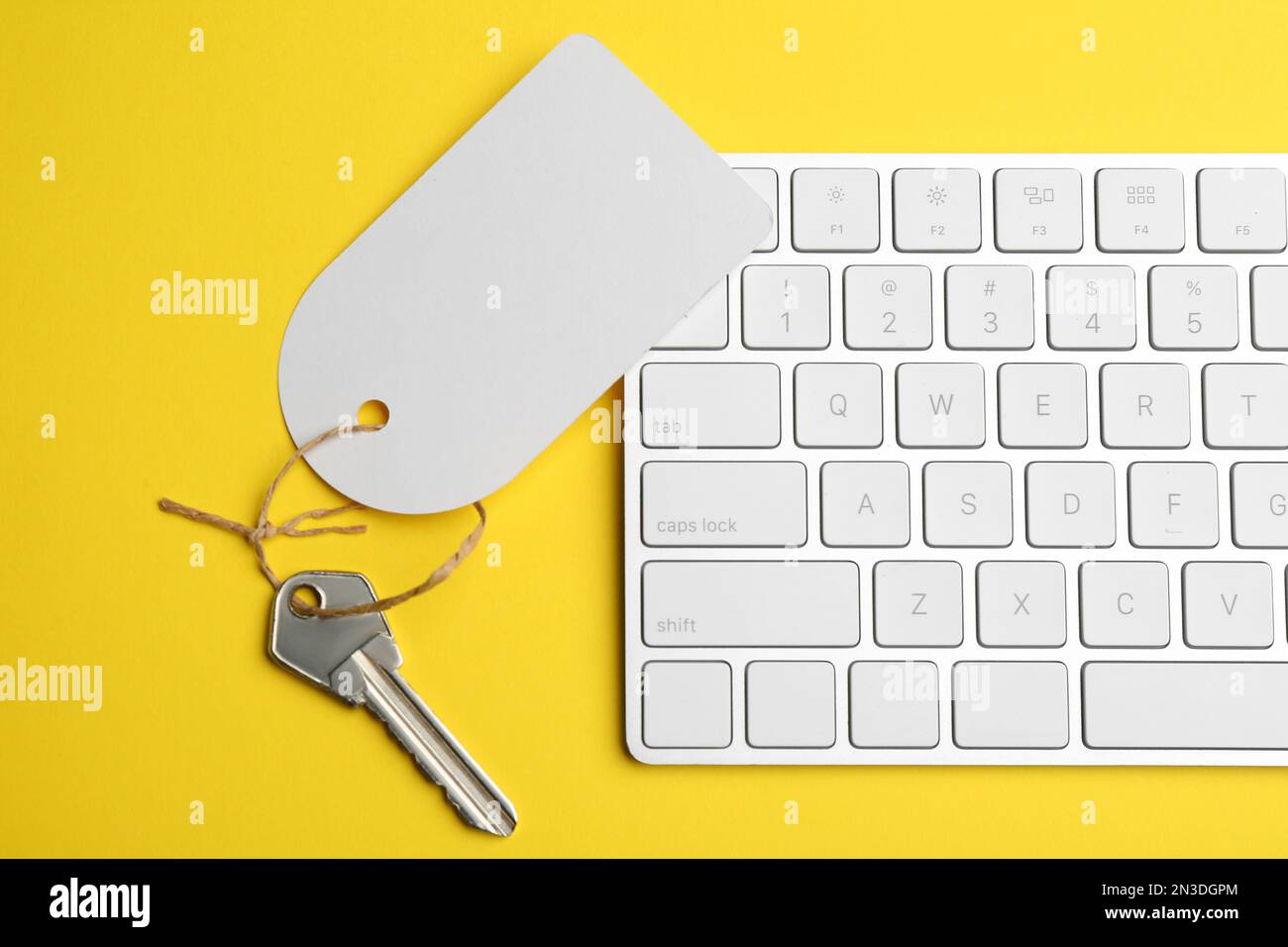 Key with blank tag and keyboard on yellow background, flat lay. Keyword ...