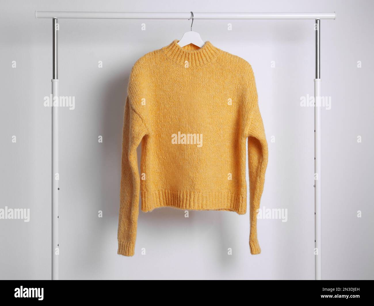 Warm sweater hanging on rack against white background Stock Photo - Alamy
