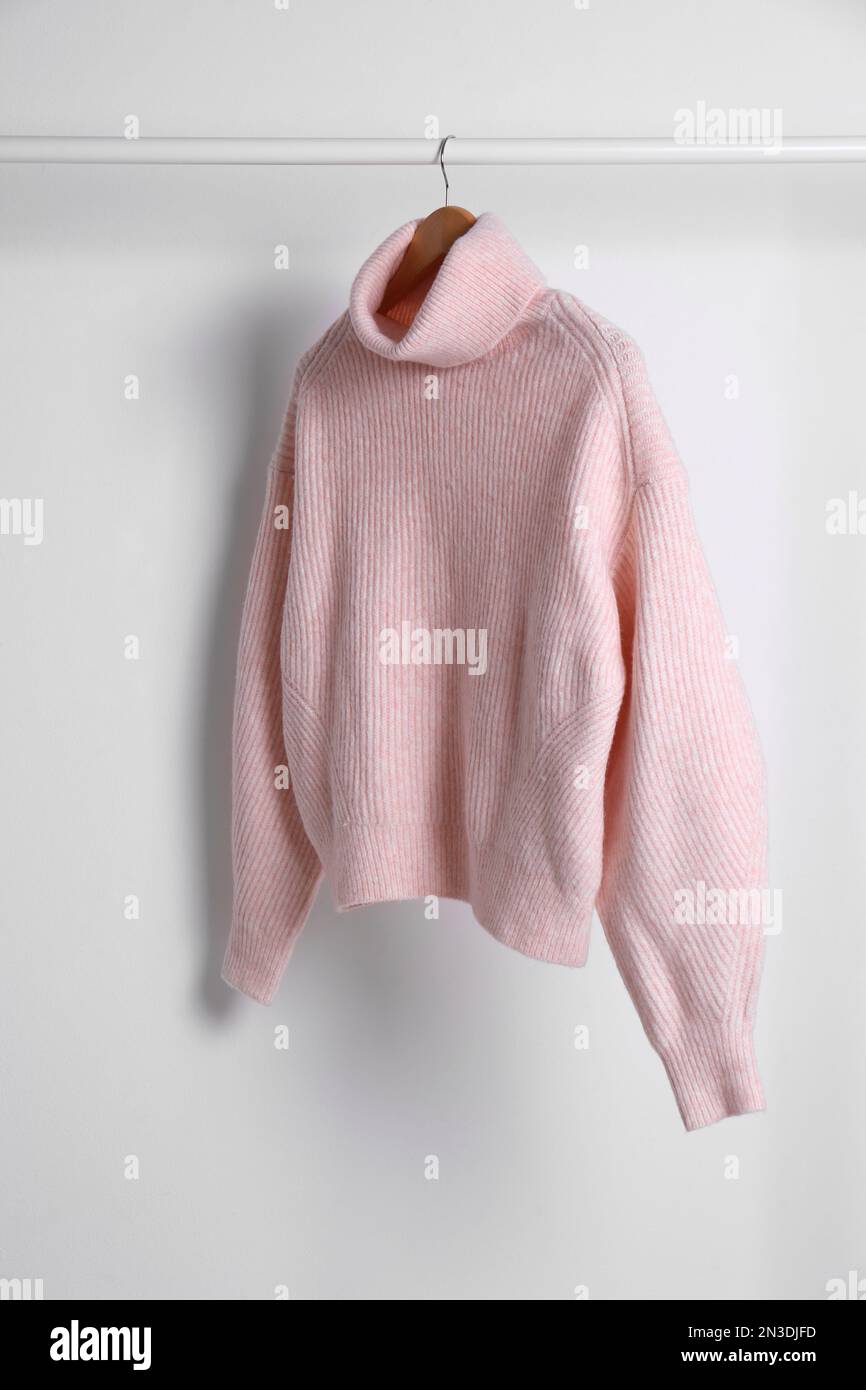 Warm sweater hanging on rack against white background Stock Photo - Alamy