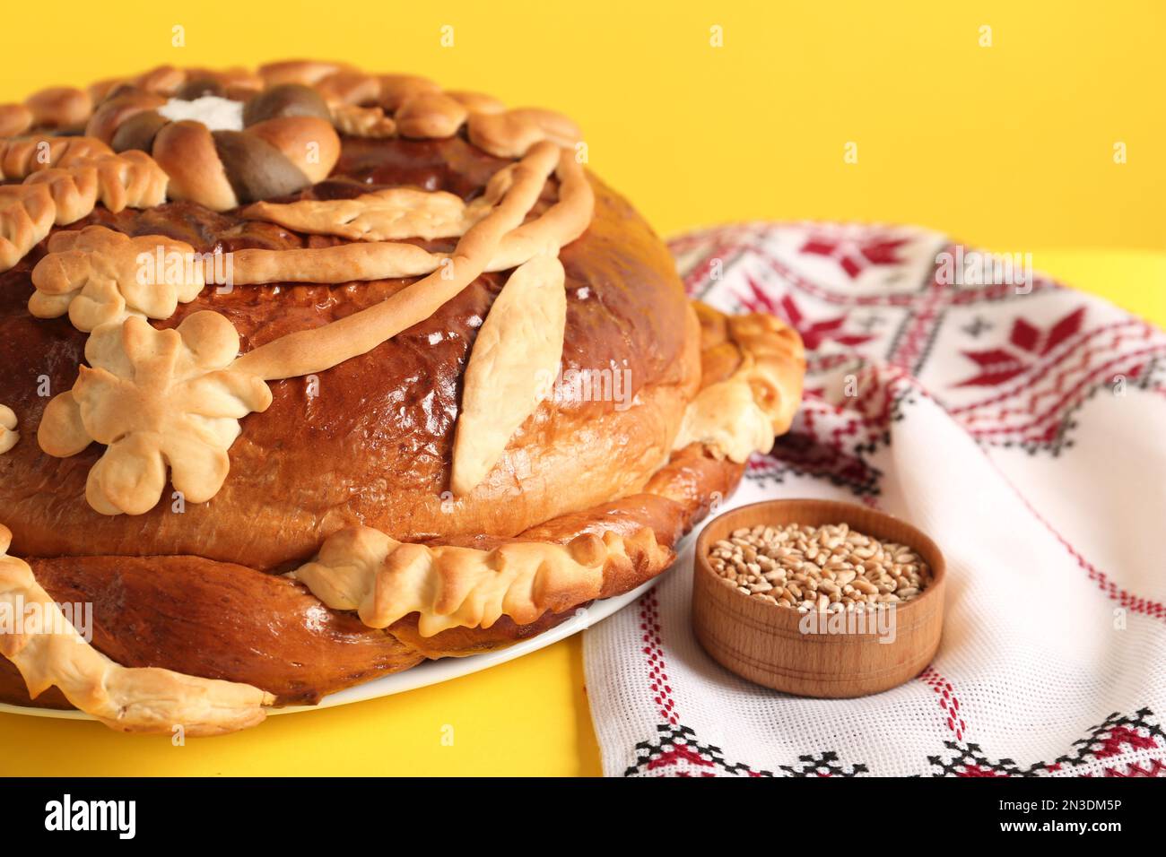 Rushnyk with korovai on yellow background, closeup. Ukrainian bread and ...
