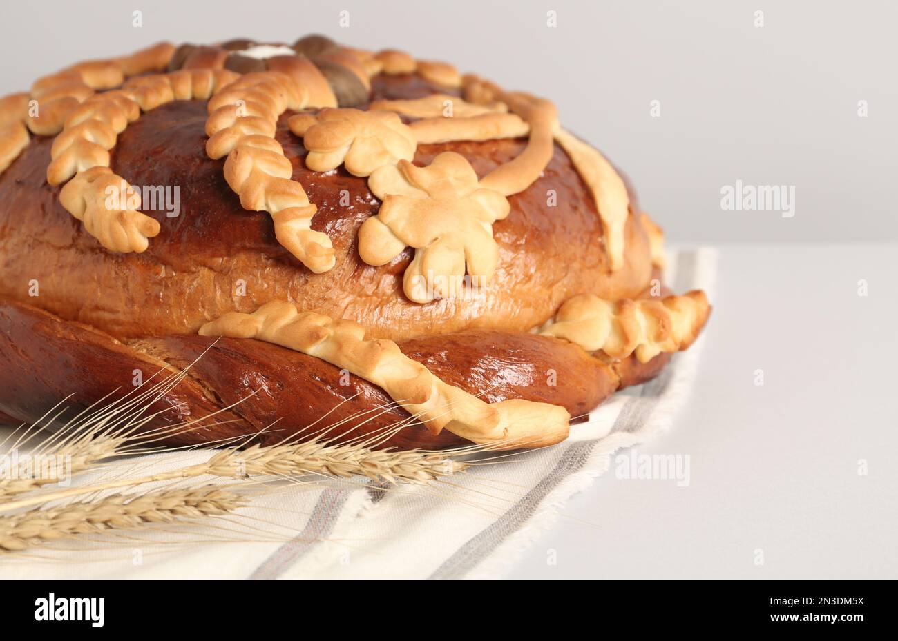 Korovai with wheat spikes on white table, closeup. Ukrainian bread and ...