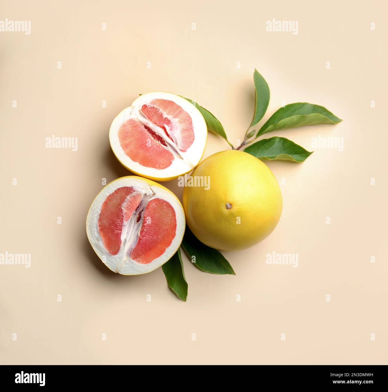 Fresh cut and whole pomelo fruits with leaves on beige background, flat ...