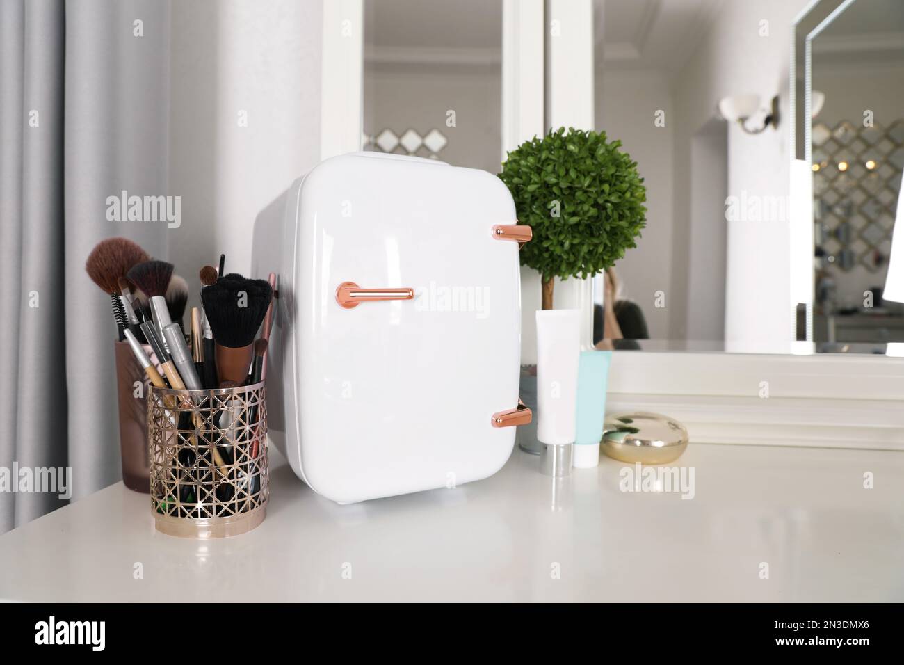 Mini fridge for cosmetic products on white vanity table Stock Photo - Alamy