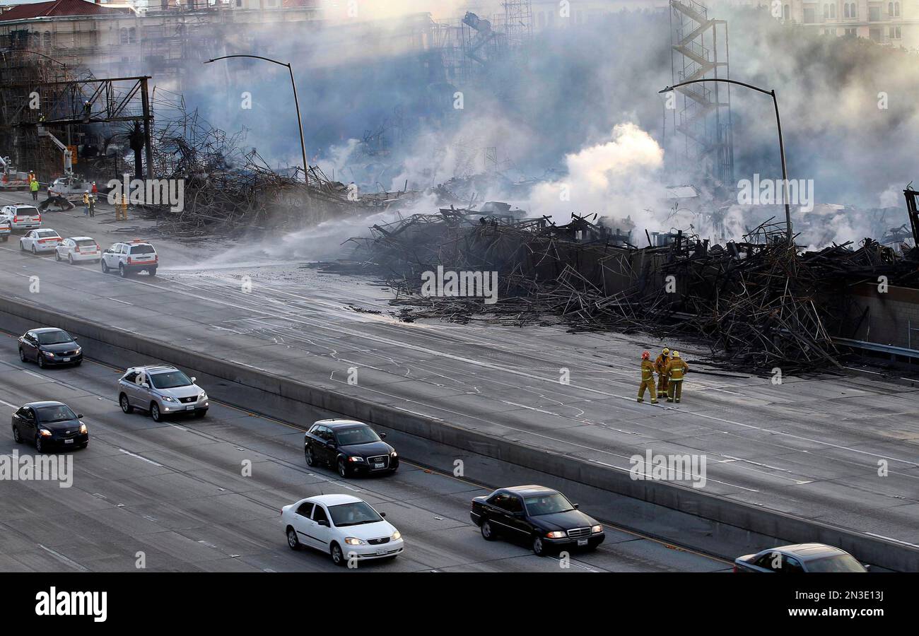 Los Angeles firefighters and state highway workers watch as an ...